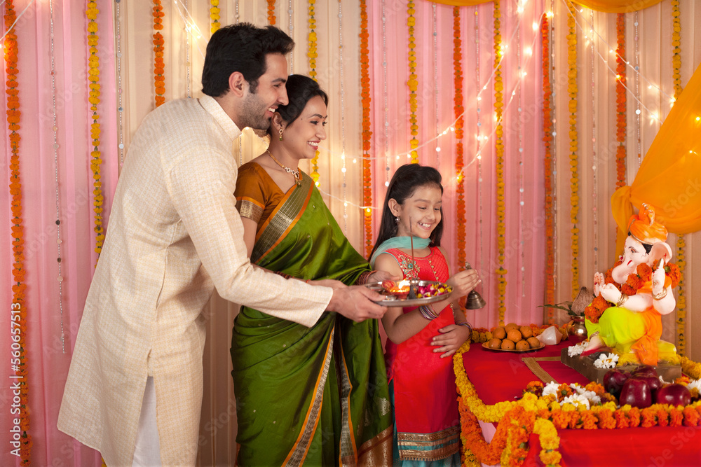 An Indian family dressed in traditional clothes performing aarti during ...