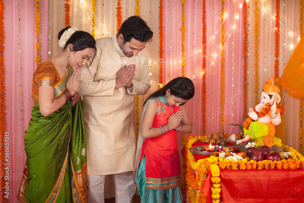 Spiritual Indian family with folded hands praying to Lord Ganesha idol ...
