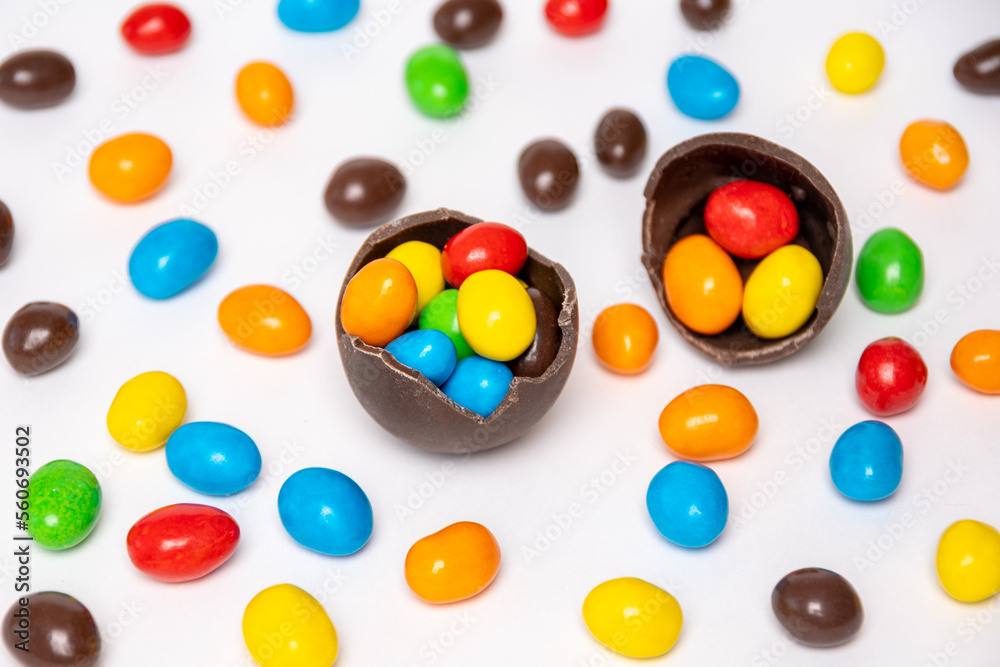 Half of a cracked chocolate egg filled with multi-colored candies on a ...