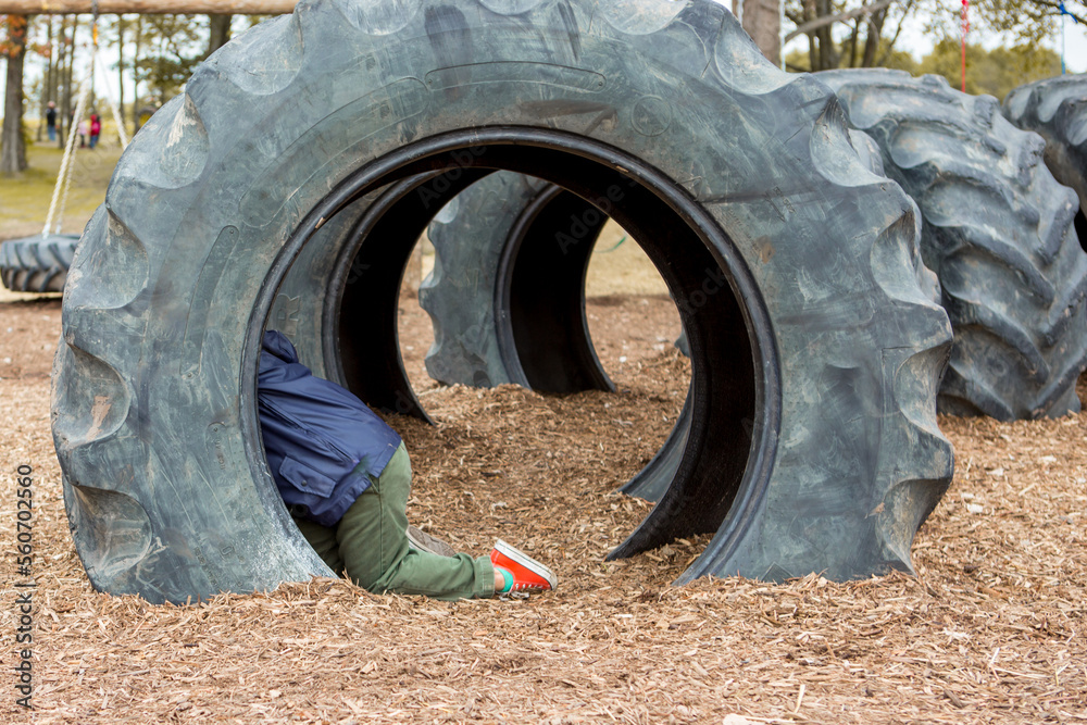 Boy hiding in a giant tire crawling maze Stock Photo | Adobe Stock