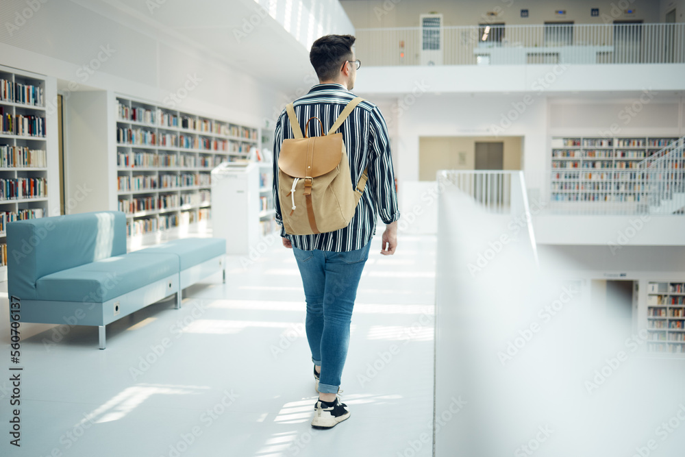 Backpack, library and education with a man student walking in a ...