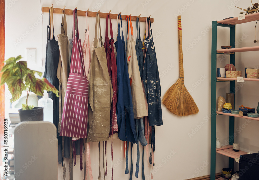 Clothes rack, apron and paint with a broom in an empty workshop or ...
