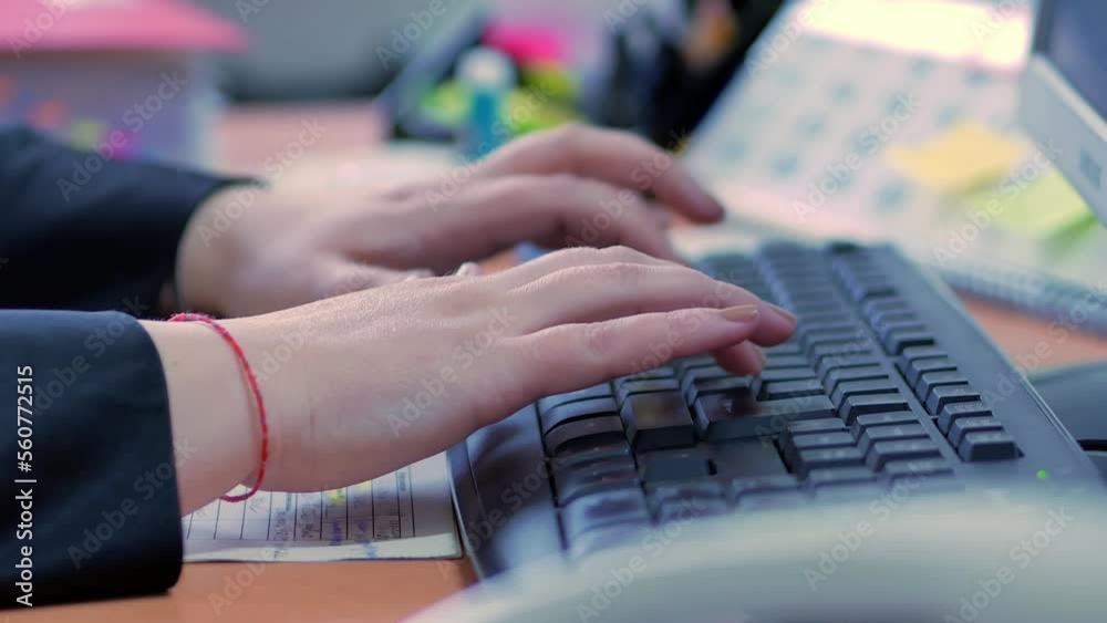Women's hands with a red thread on the wrist hit the keyboard buttons ...
