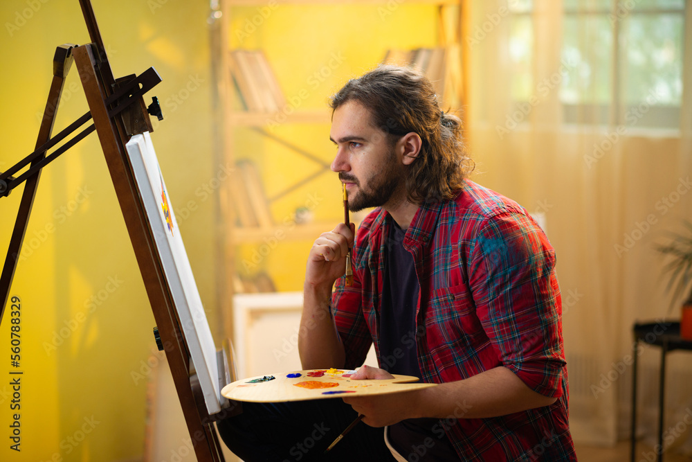 A painter is painting a very detailed piece of art on his blank canvas ...