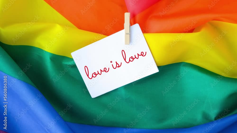4k zoom in out Rainbow flag with text LOVE IS LOVE message on paper ...