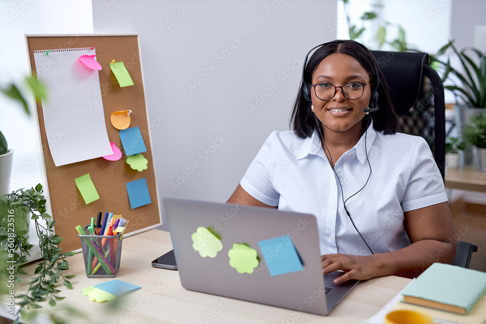 Adorable smiling black female dispatcher with microphone working alone ...