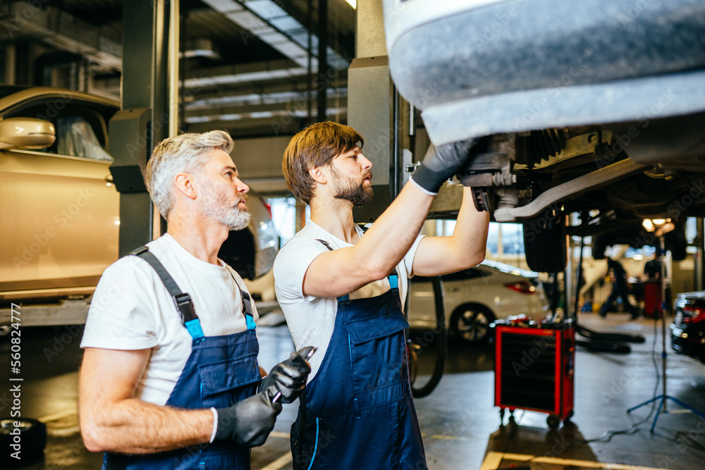 Two car mechanic father and son diagnosing vehicle at the auto service ...