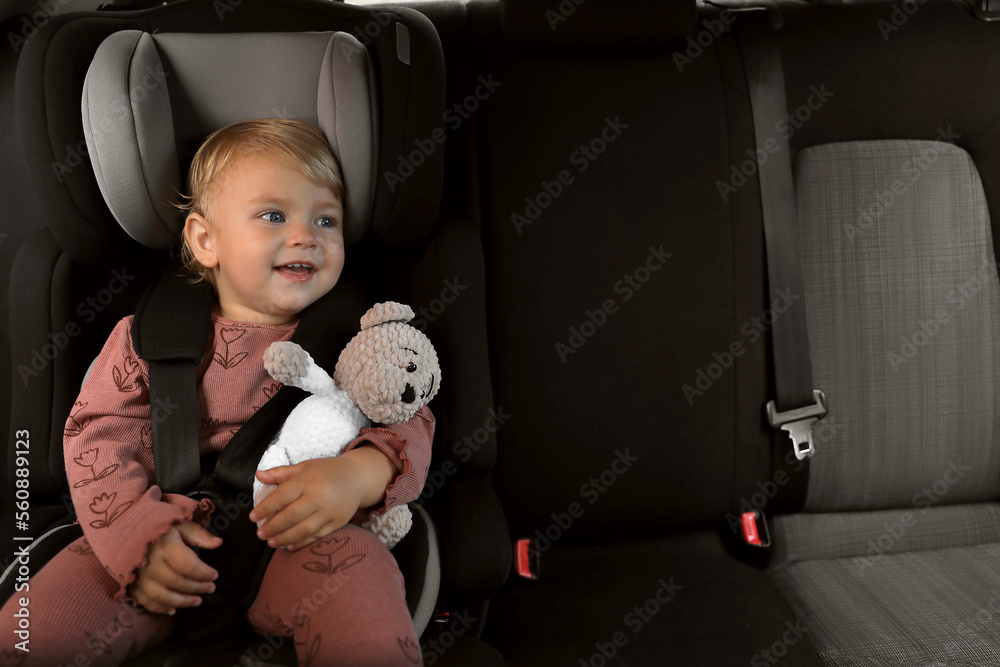 Cute little girl sitting in child safety seat inside car Stock Photo ...