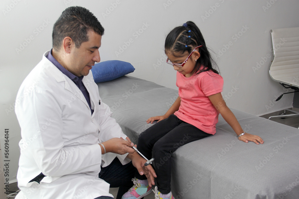 Latino doctor medic and girl patient in medical office checks her ...