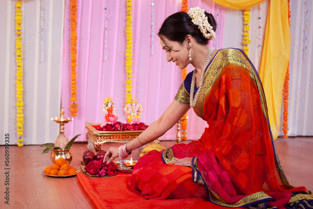 Young traditional Indian woman preparing for puja rituals using rose ...
