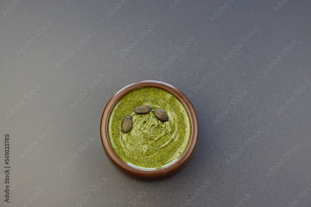 Green pumpkin seed paste in a brown round bowl on a gray background ...