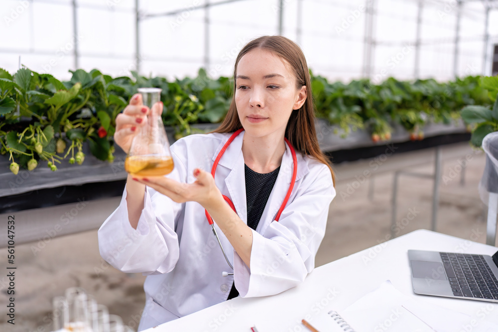 Doctor nutritionist in greenhouse farming proudly showing bottle of ...