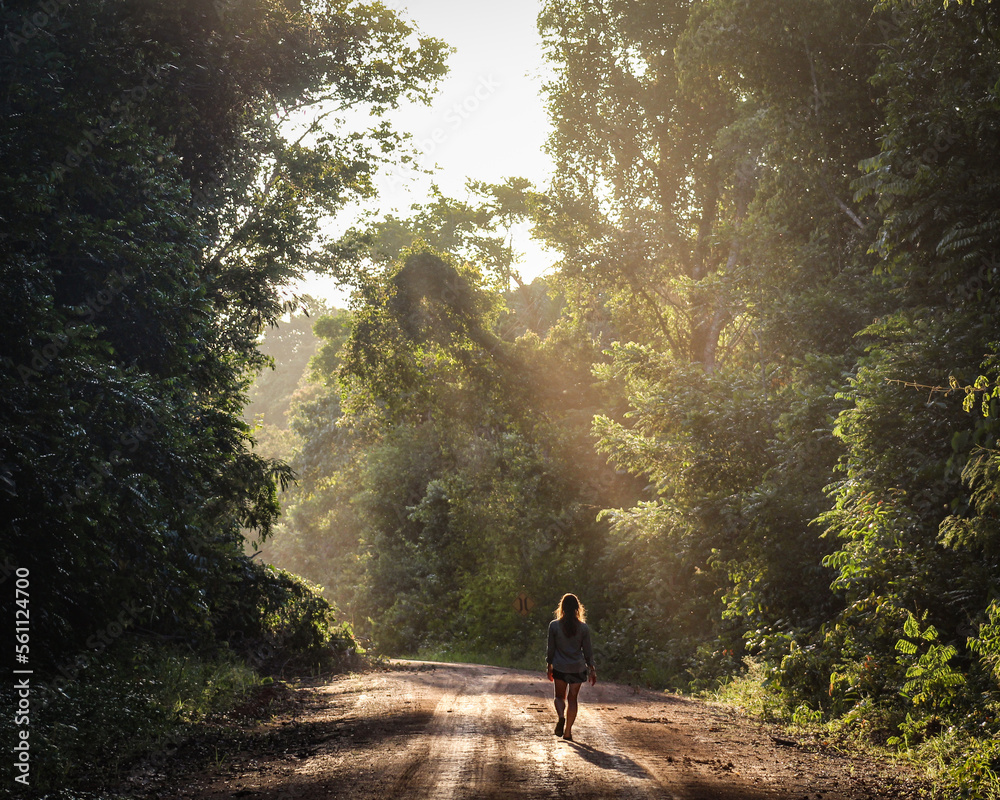 Stockfoto Mulher caminhando em estrada iluminada por raios de sol na ...