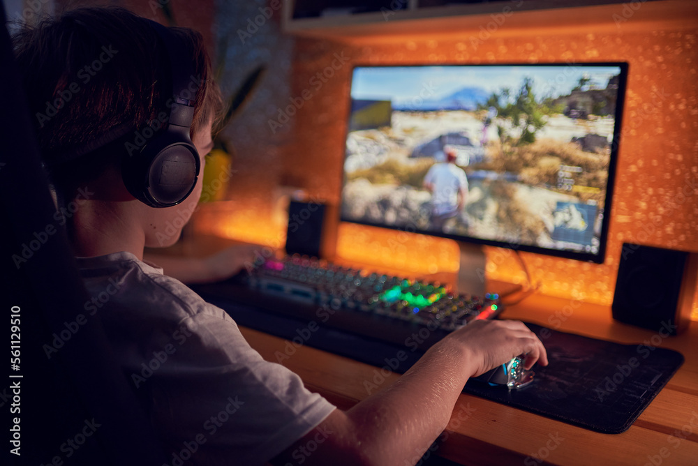 Hands of teenage gamer boy playing video games on computer in dark room ...
