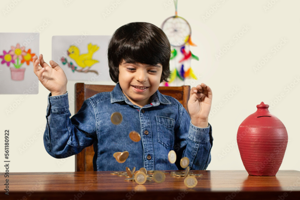 Young joyful boy playing and counting his saved coins and thinking ...