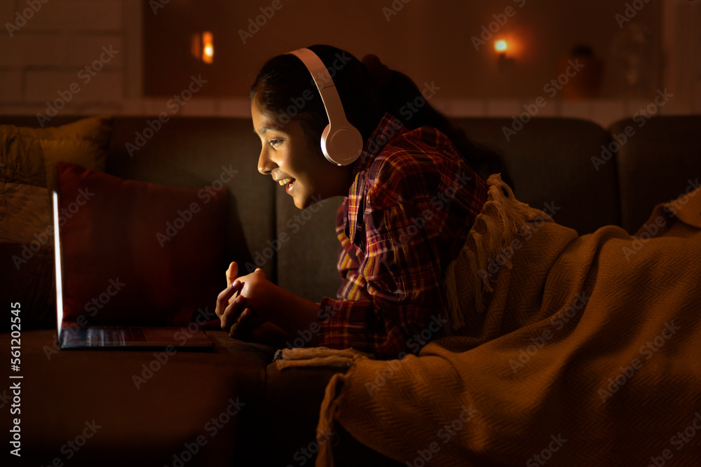 Girl watching video on laptop while lying down on sofa in living room ...