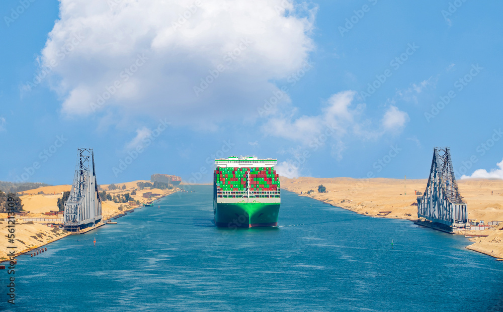 Large container ship, accompanied by tugboat, passing through the Suez Canal in Egypt. Railway ...