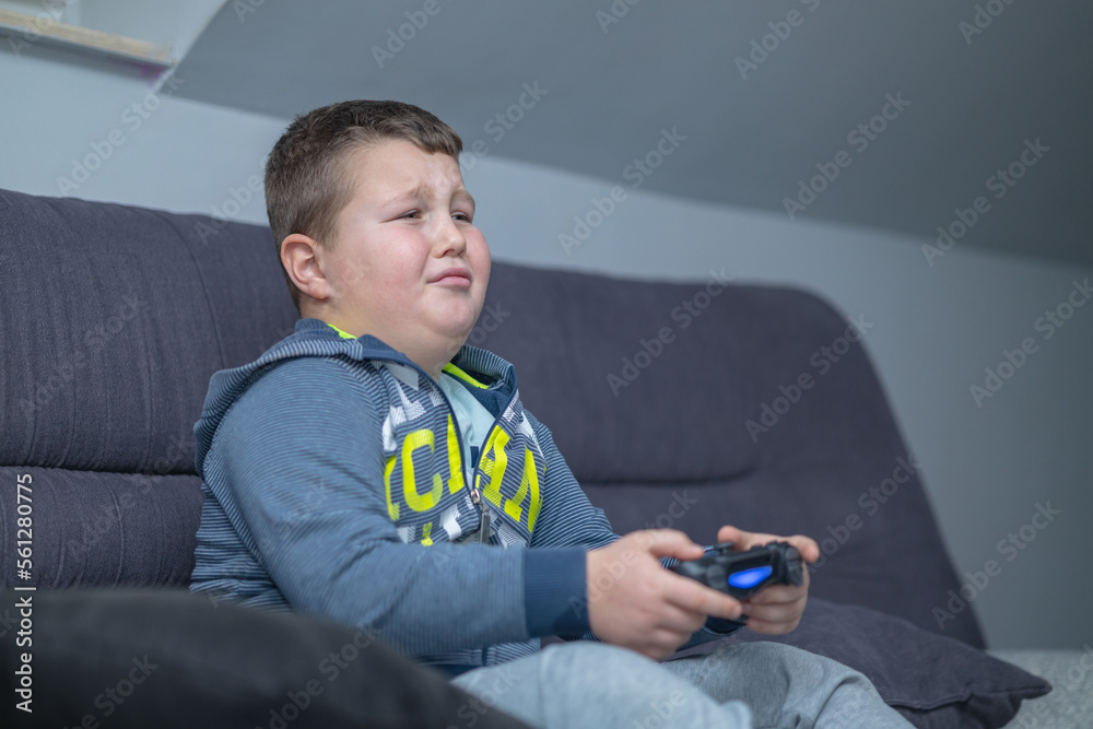 the boy is sitting on the couch, holding a joystick and playing a video ...