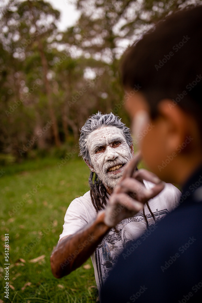 Aboriginal man wearing white face paint putting white face paint onto a ...