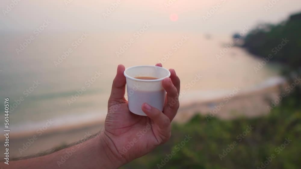 Closeup shot of hand of an Indian man holding tea cup in front of the ...