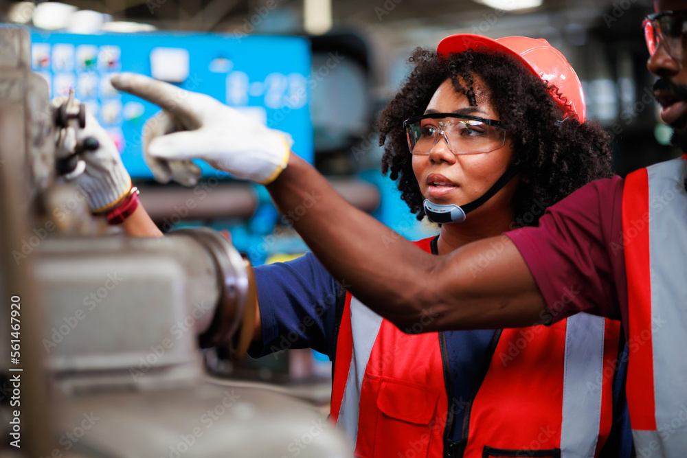 Black Woman worker wearing safety goggles control lathe machine to ...