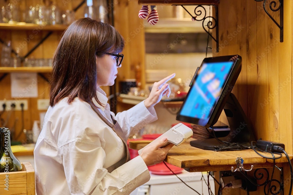 Female restaurant worker using computer terminal while serving ...