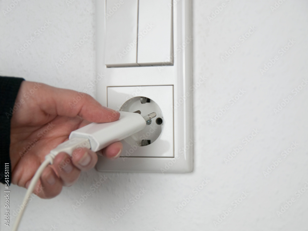 Energiekosten und Stromverbrauch: Hand beim Einstecken eines weißen ...