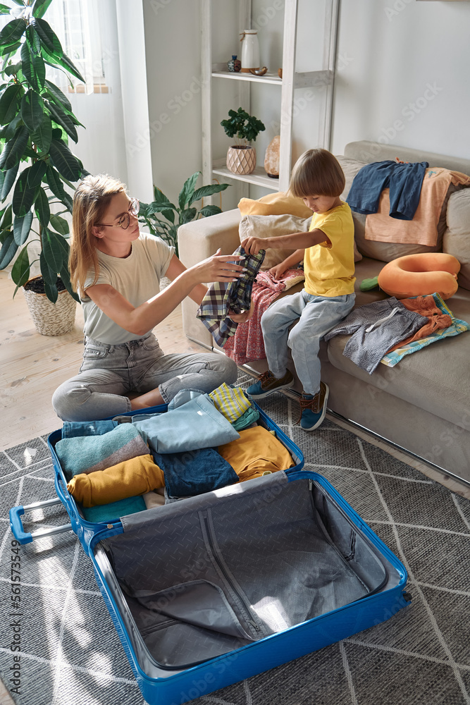 Family mother and child packing a suitcase together going on a trip or ...