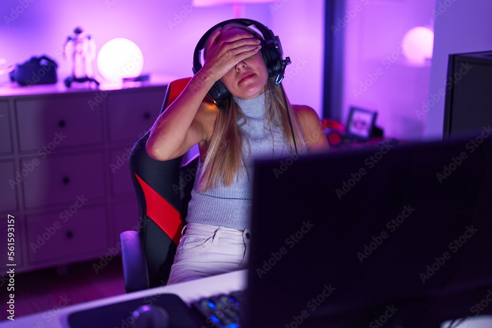 Young blonde woman streamer stressed using computer at gaming room ...
