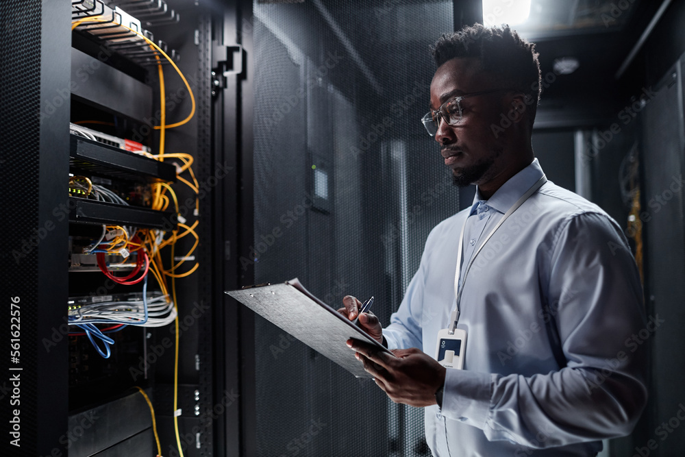Waist up side view portrait of network engineer working with server ...