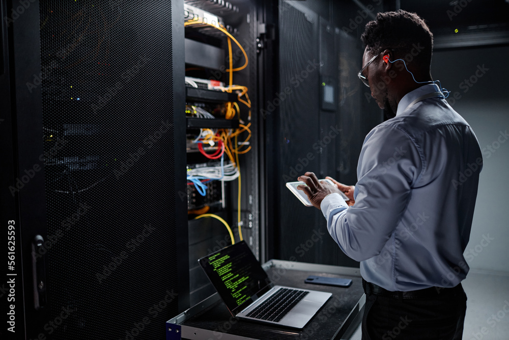 Side view portrait of network engineer using laptop while setting up ...