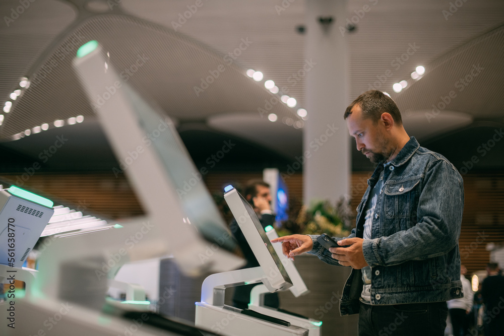 A male passenger at the electronic check-in desk in the departure area ...