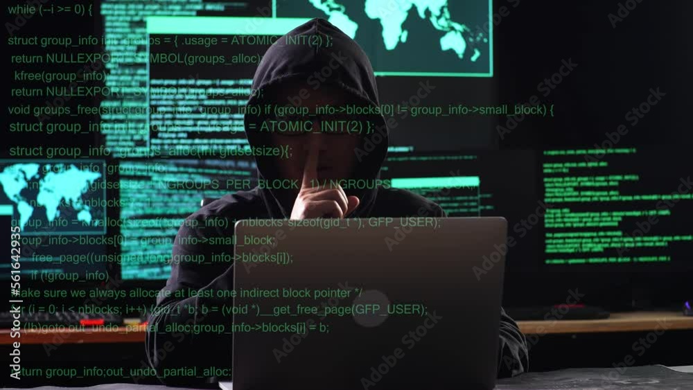 Asian Male Hacker In A Hood Showing Shh Gesture While Works On A Laptop ...