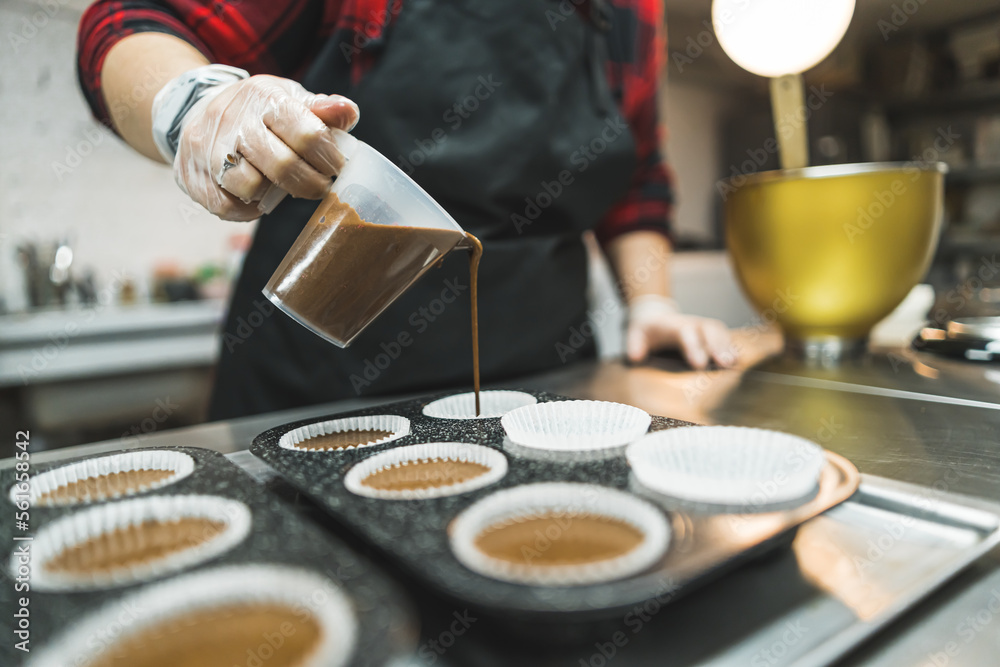Female professional baker wearing black apron pouring out chocolate ...