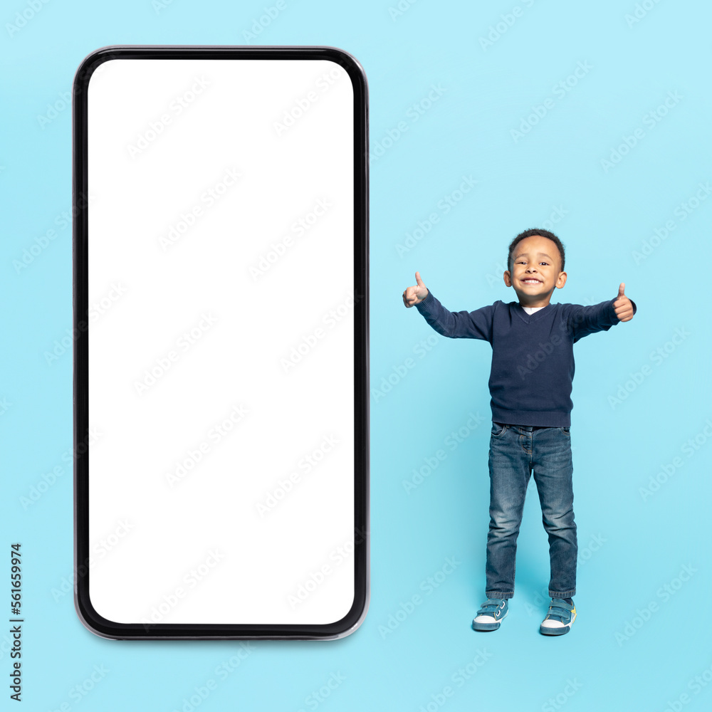 Cute african american child boy standing by big smartphone with white ...