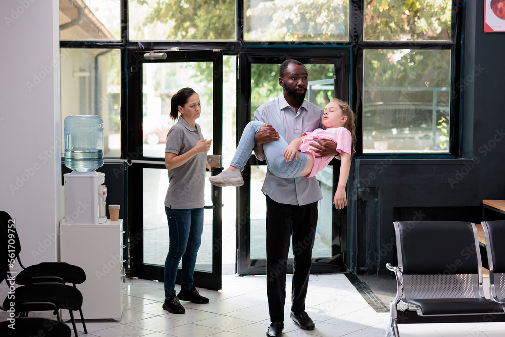 Worried african american dad holding unconscious daughter in arms after ...
