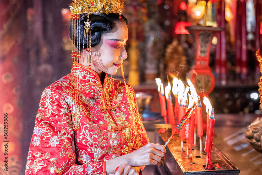 Woman traditional dress in Chinese shrine light up candle joss stick ...