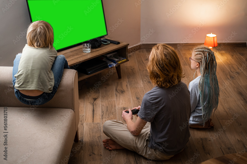 Three children playing video game Green screen chromakey on tv console ...