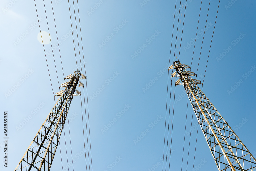 Two pillars viewed from below, with parallel electricity cables in a ...
