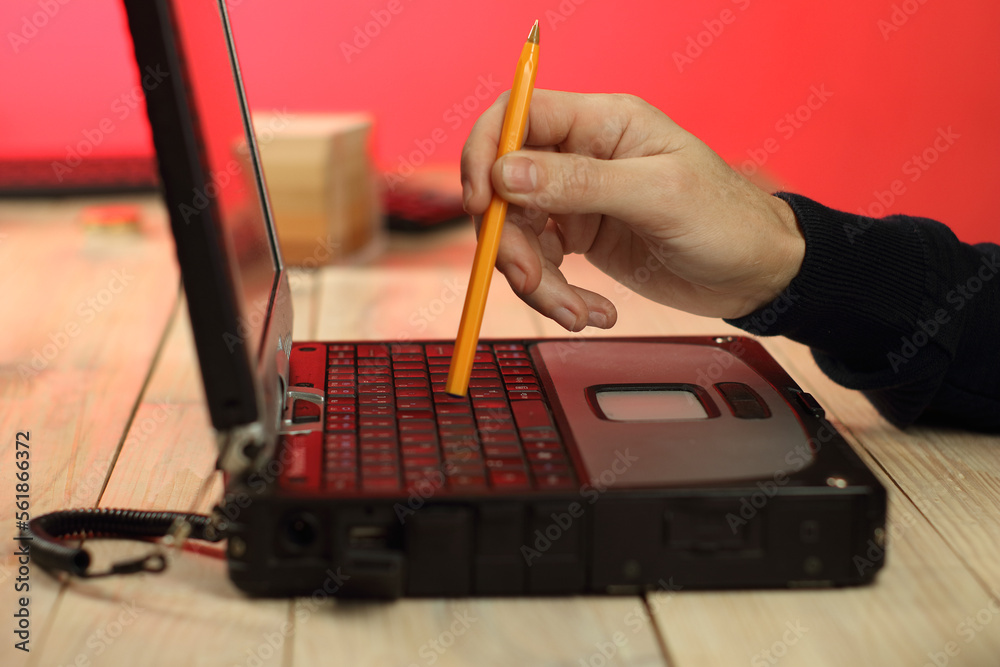 punching letters with a pen on the keyboard of an old laptop by a ...