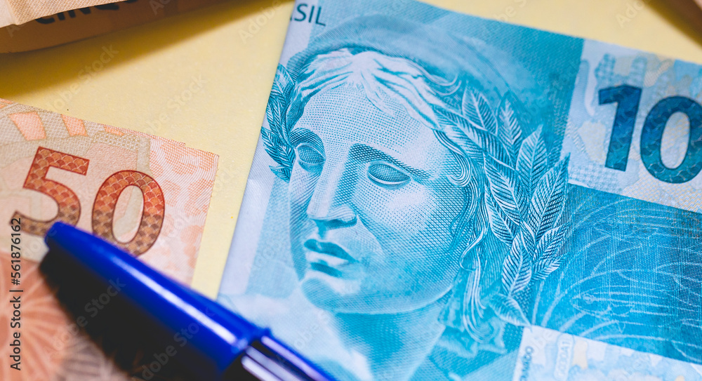 Notas do Real Brasileiro em fotografia macro. Fundo com papel amarelo e ...