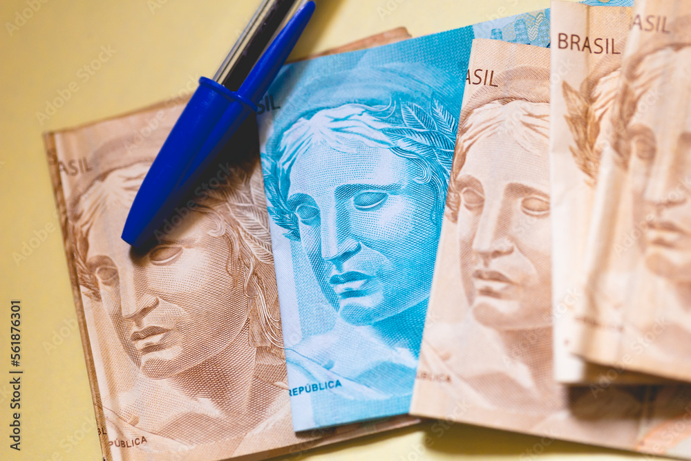 Notas do Real Brasileiro em fotografia macro. Fundo com papel amarelo e ...
