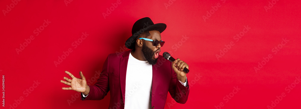 Passionate black male singer performing against red background, singing ...