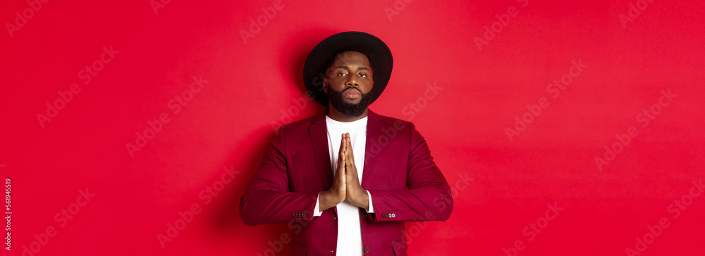 Serious african american man showing respect, holding hands together in ...