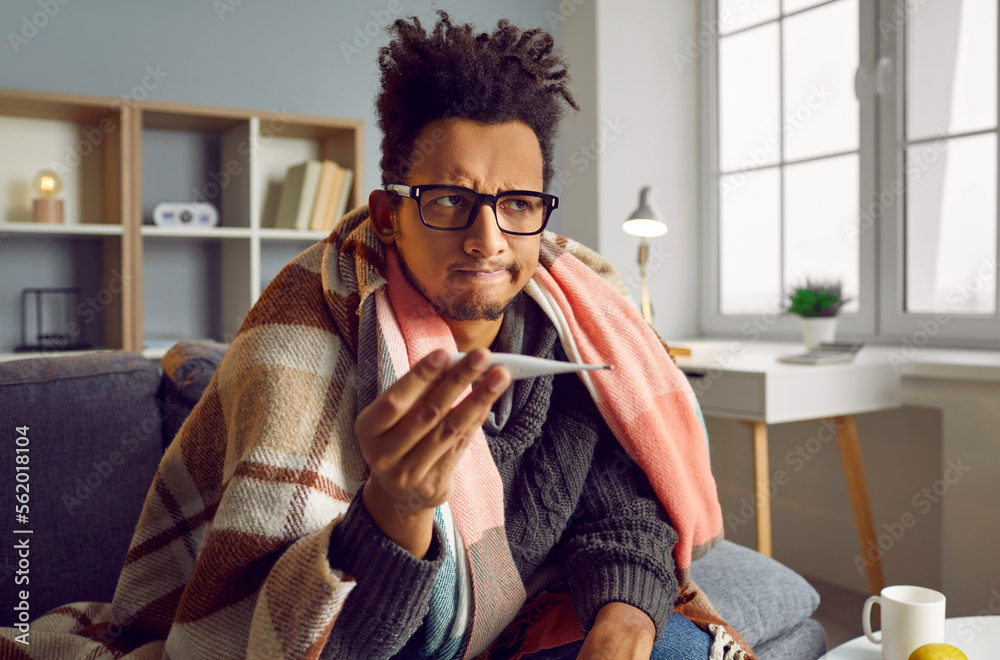 Portrait of a sad sick young african american man in glasses checking ...