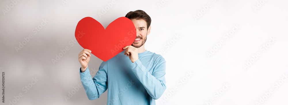 Smiling handsome man holding romantic red heart over half of face ...