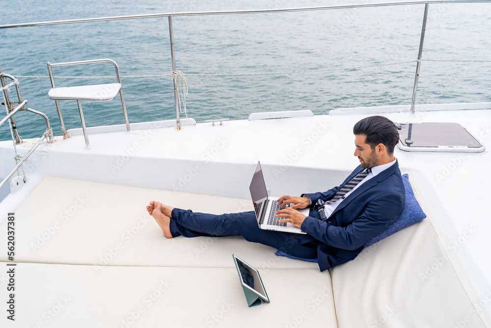 Confident businessman working on laptop computer and talking on mobile ...