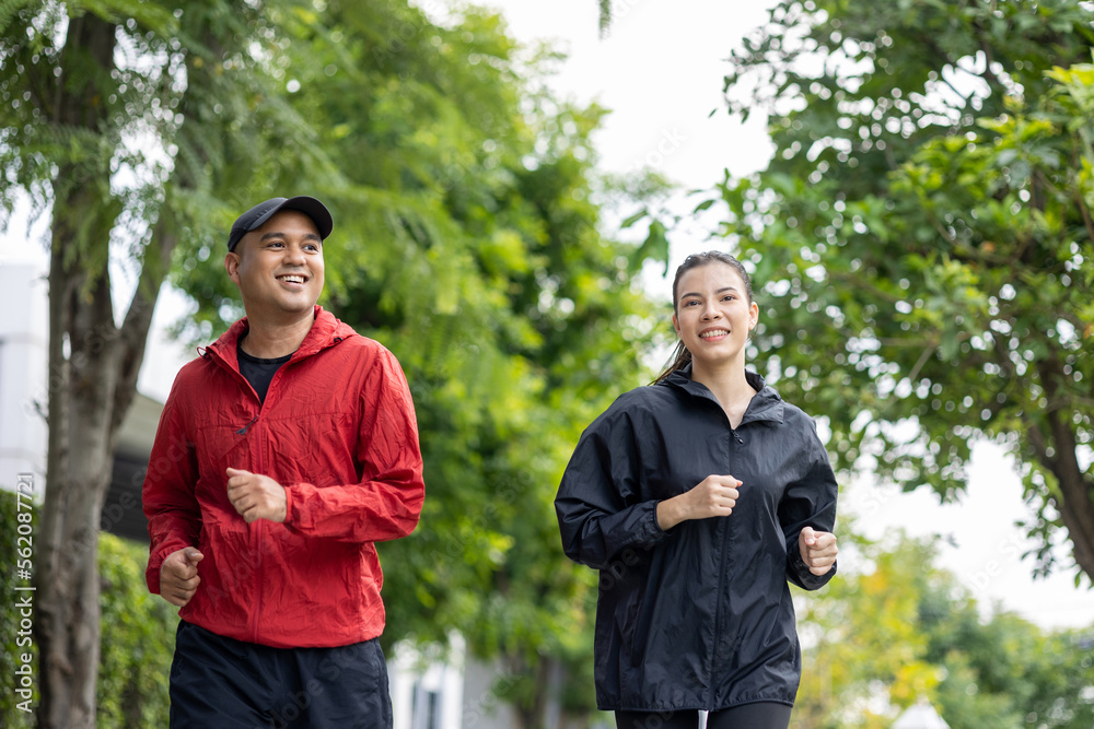 Couple jogging and running outdoors in nature. Happy Man woman wearing ...