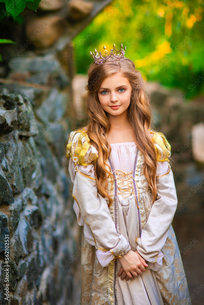 Beautiful young blonde princess in gold medieval dress and little crown ...