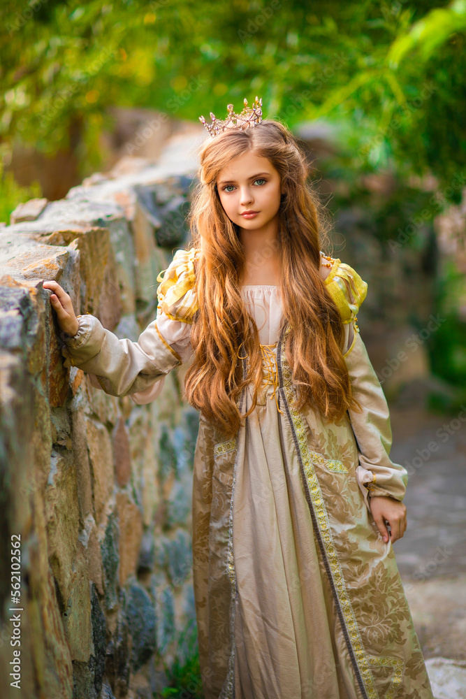 Beautiful young blonde princess in gold medieval dress and little crown ...
